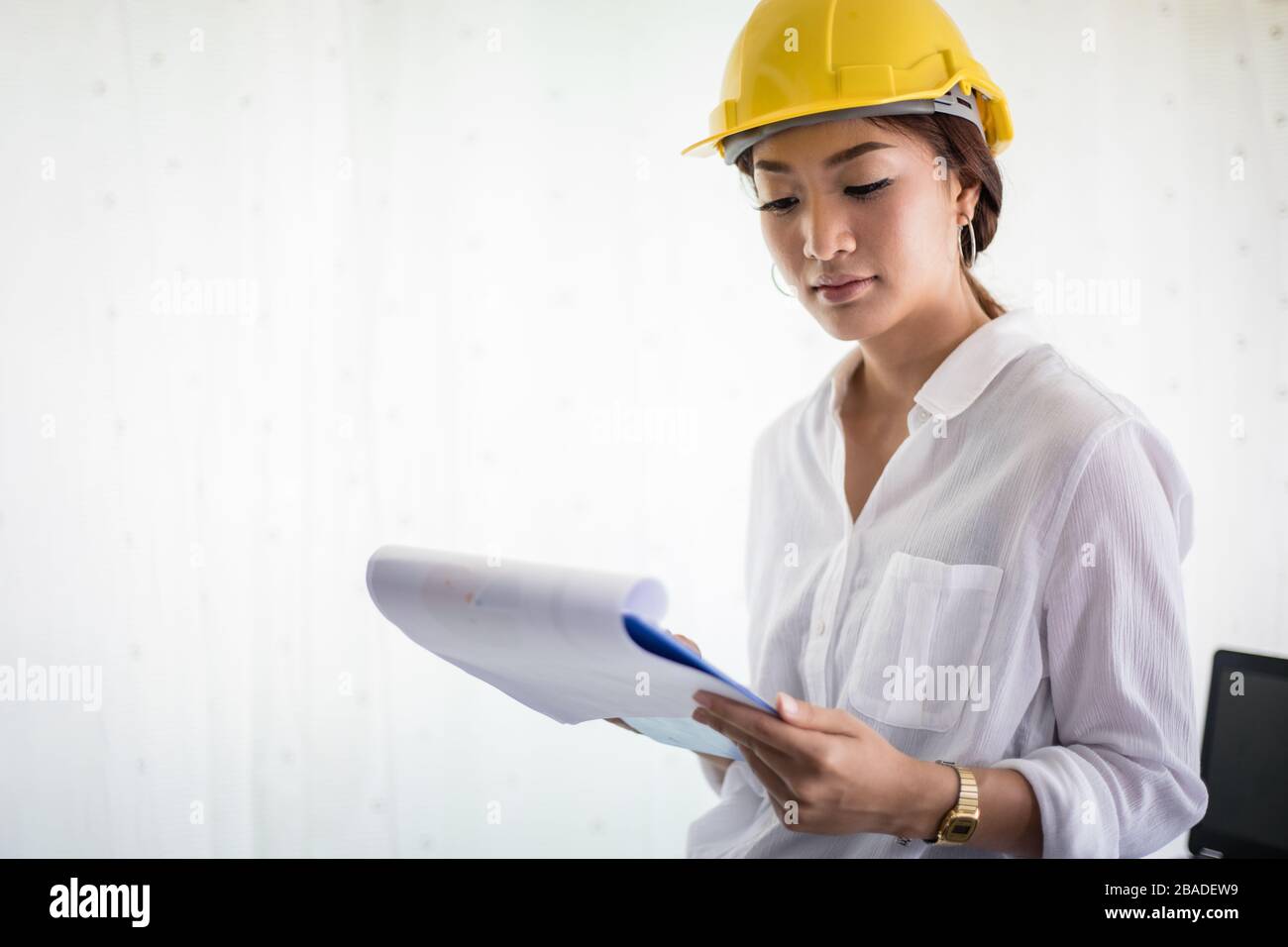 Asian women engineering inspecting and working and holding blueprints ...