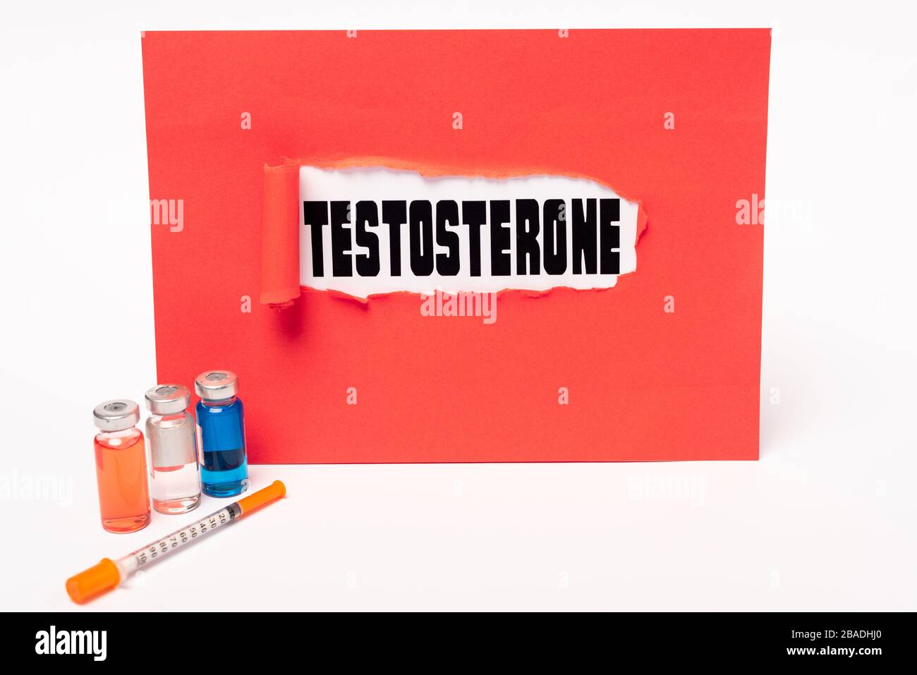 Testosterone lettering in hole of red paper, syringe and jars of ...