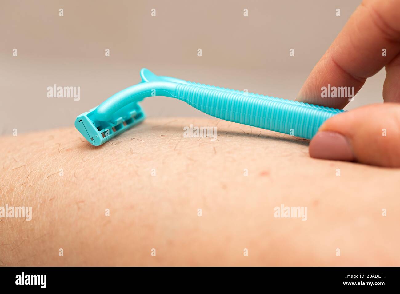 Close up picture of woman holding razor, shaving her hairy leg with ...