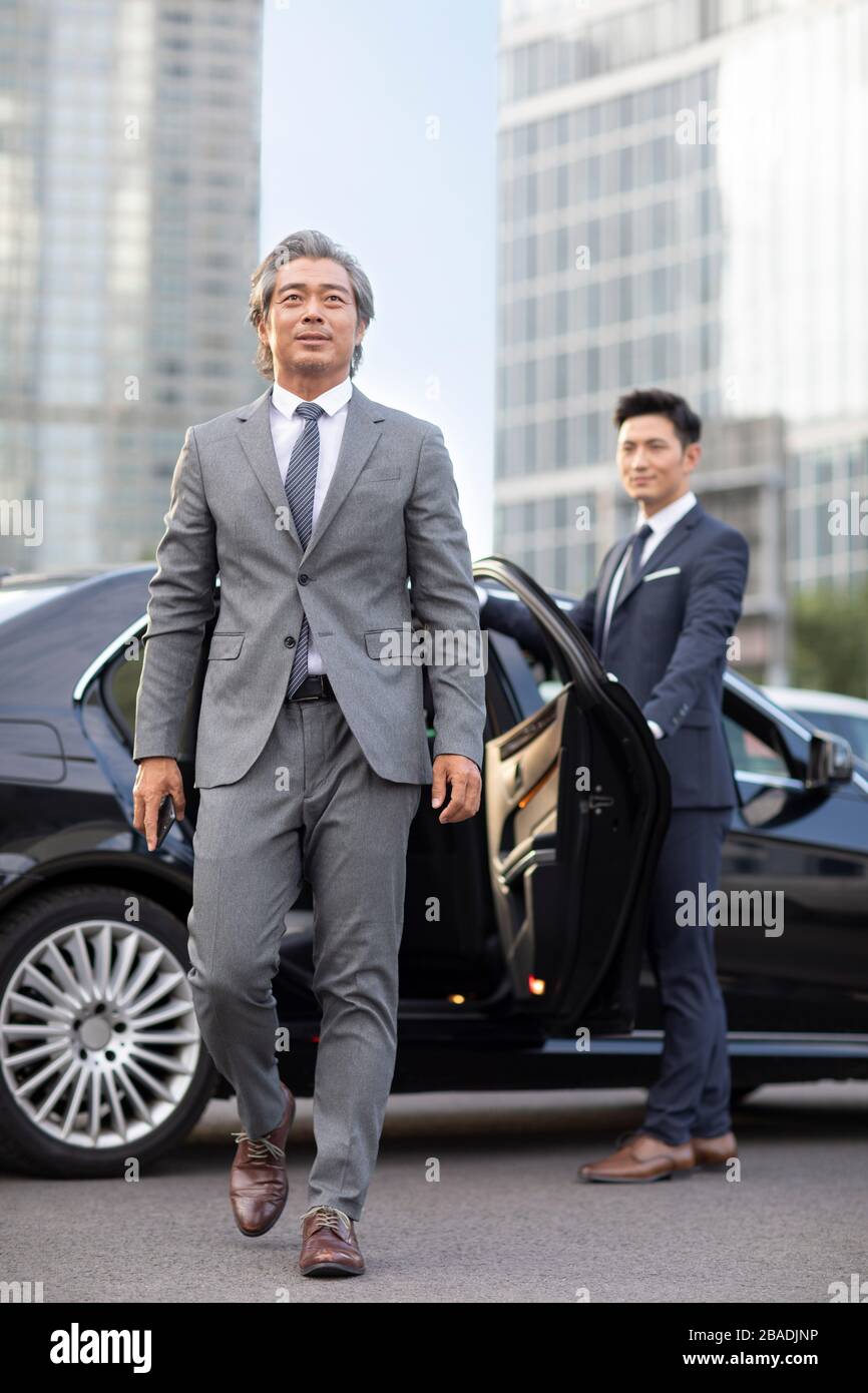 Confident Chinese businessman getting out of car Stock Photo - Alamy