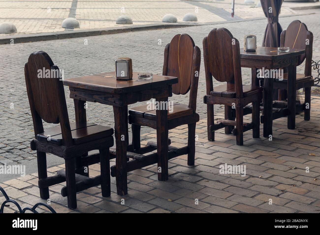 Wooden tables and chairs in a retro style street cafe without people ...