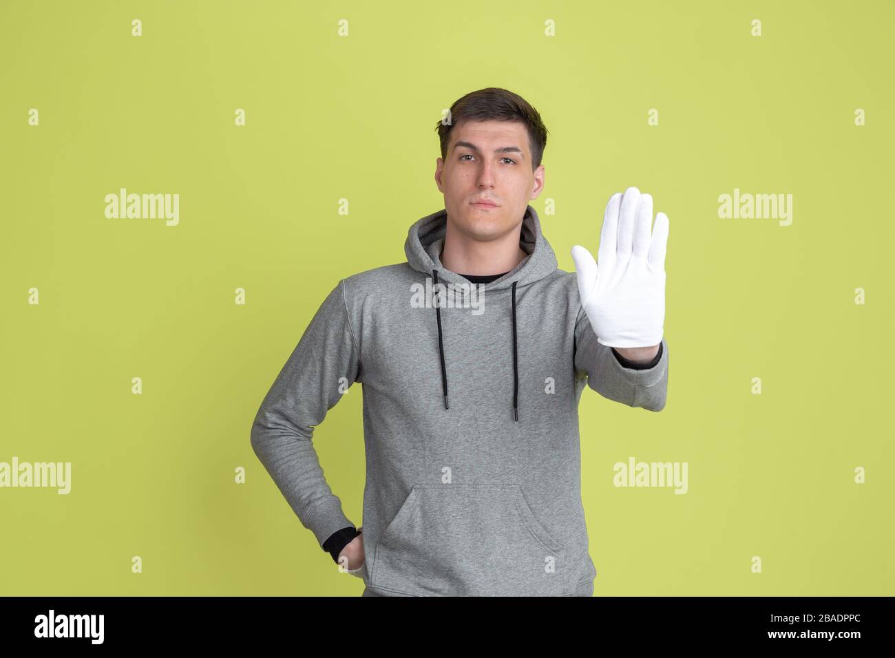 Showing stop sign. Caucasian man's portrait isolated on yellow studio ...