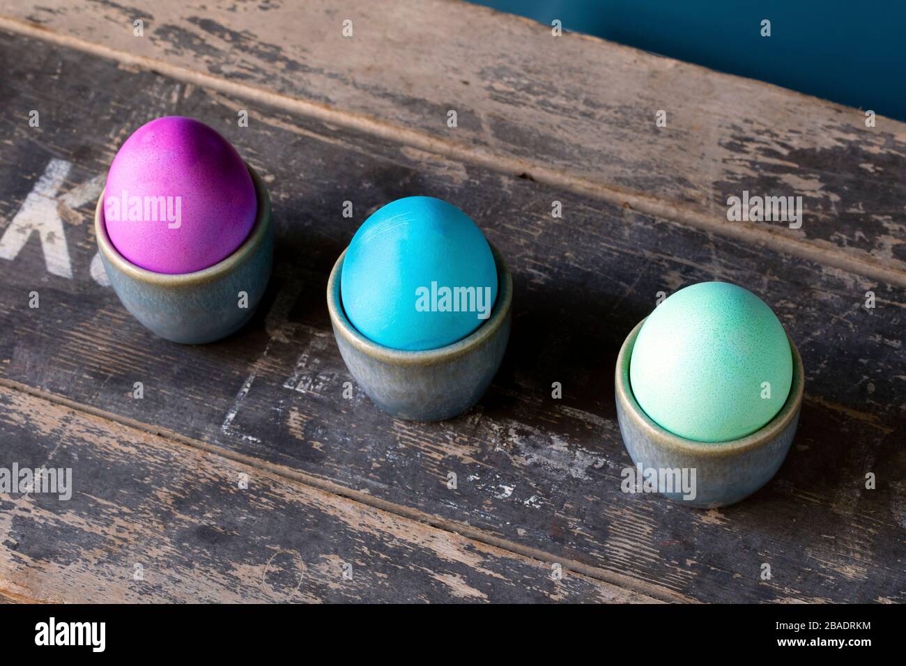 Colorful bright Easter eggs hand painted in egg cups on a blue ...