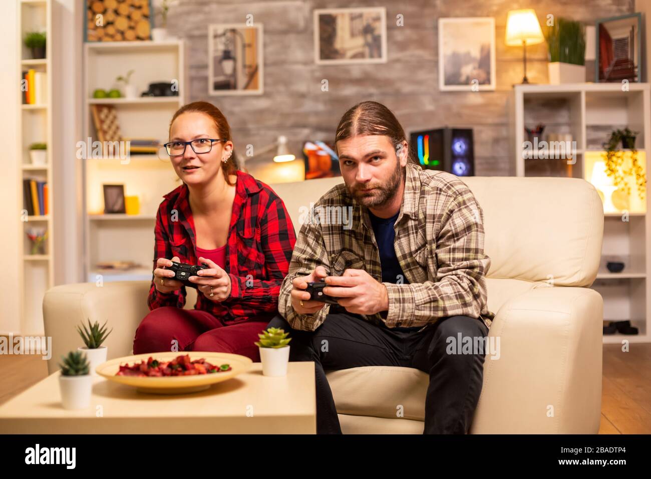 Gamers couple playing video games on the TV with wireless controllers ...