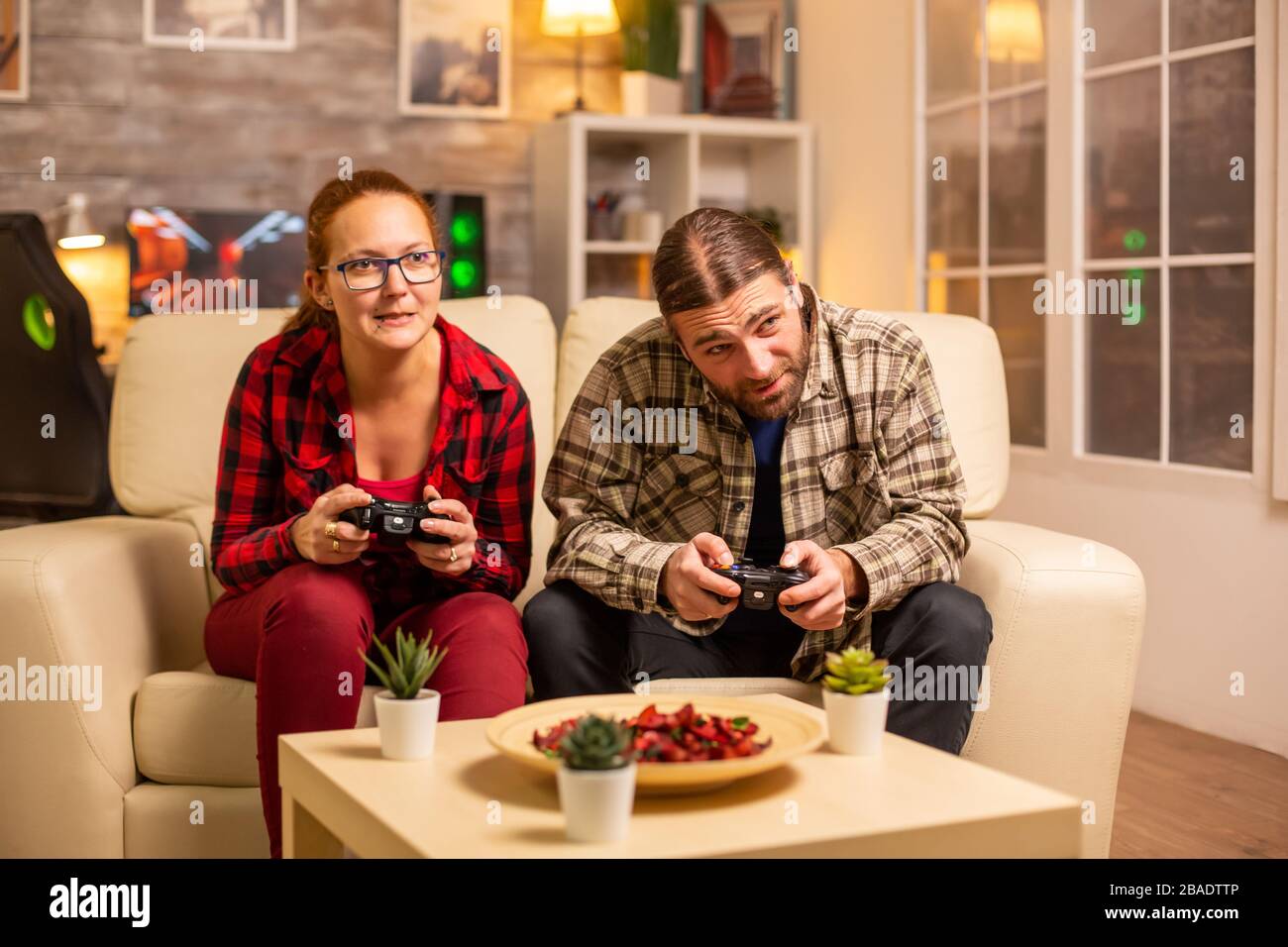 Gamers couple playing video games on the TV with wireless controllers ...