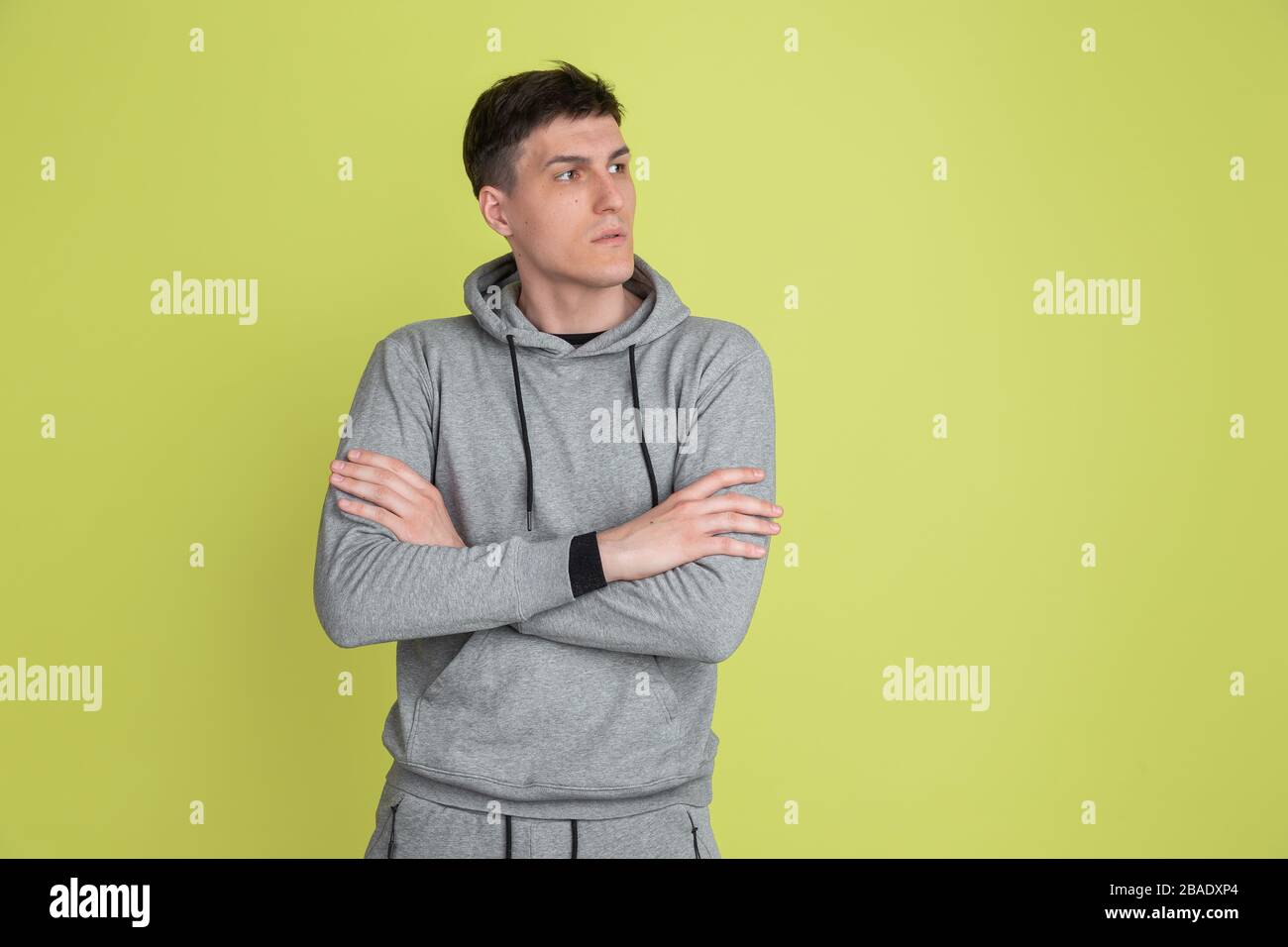 Hands crossed. Caucasian man's portrait isolated on yellow studio ...