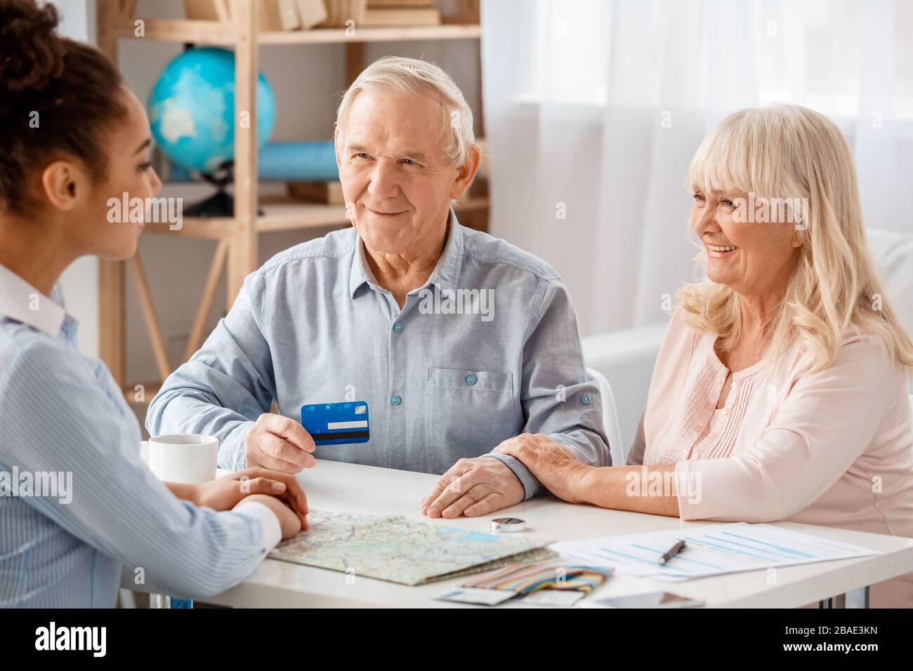 Travel agent at office sitting with senior clients man giving credit ...