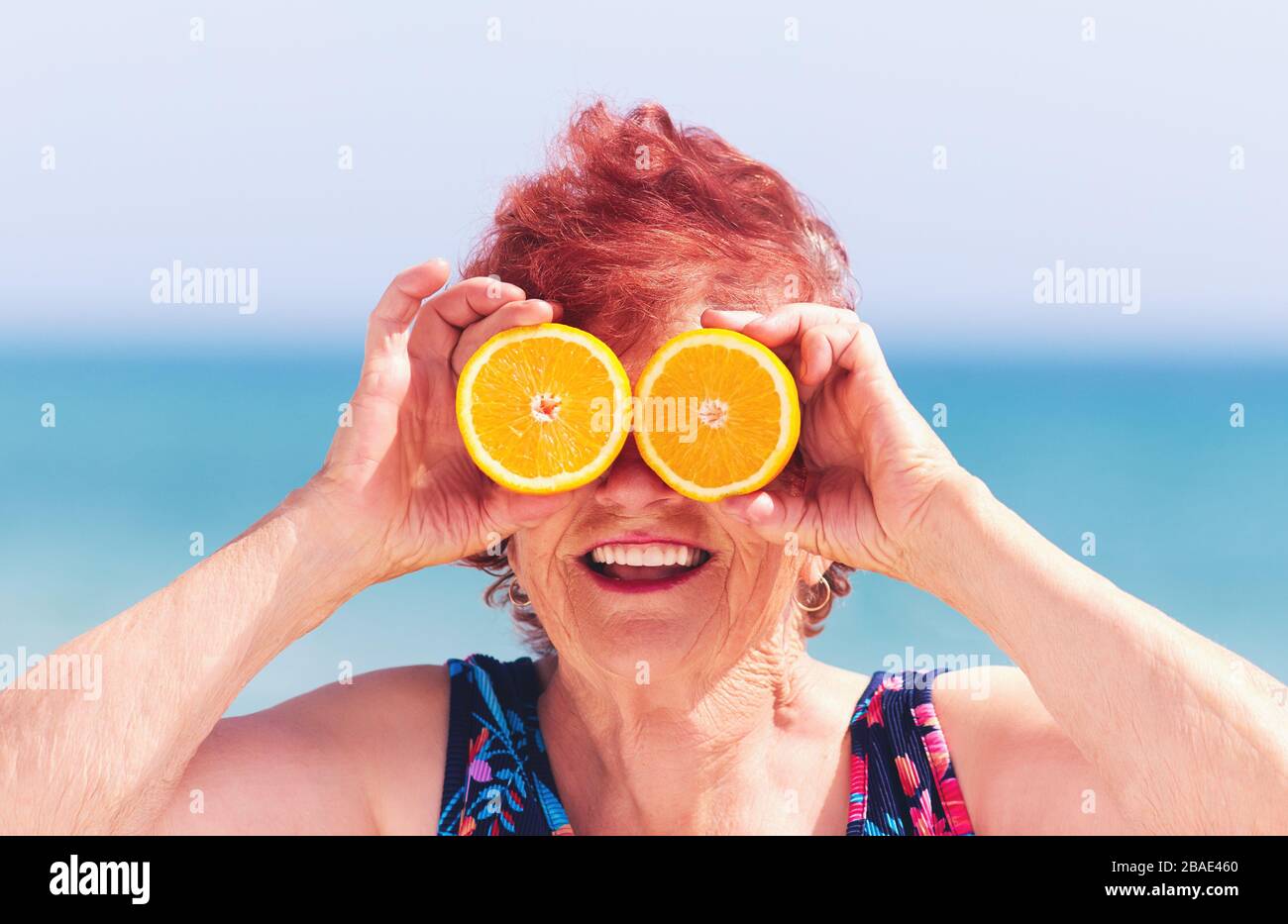 funny portrait of mature woman, grandma having fun with orange eyes on ...