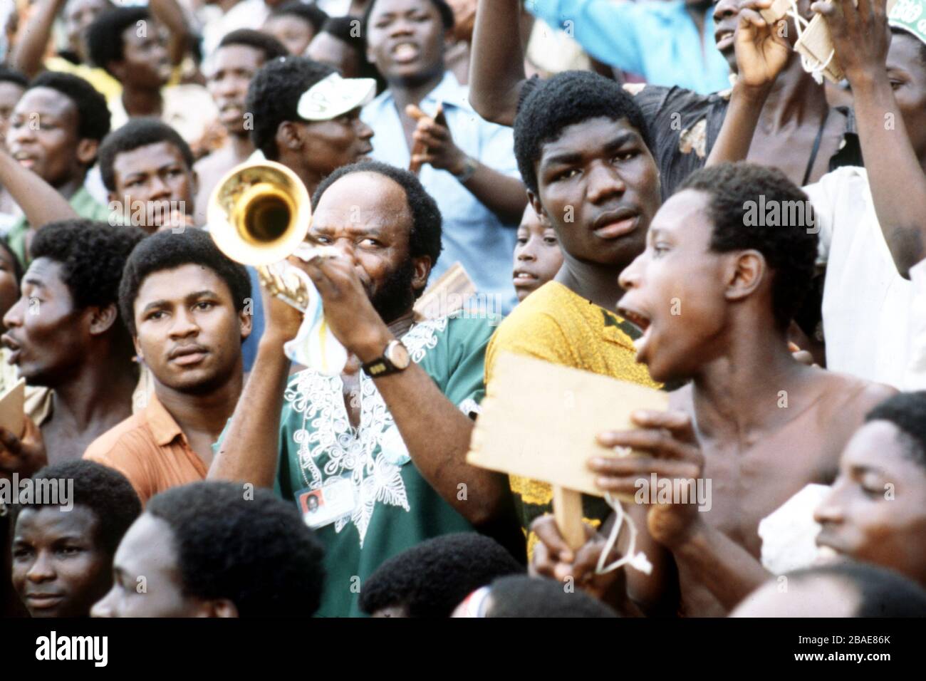 A Nigeria fan plays a trumpet to rouse his neighbours in the crowd ...