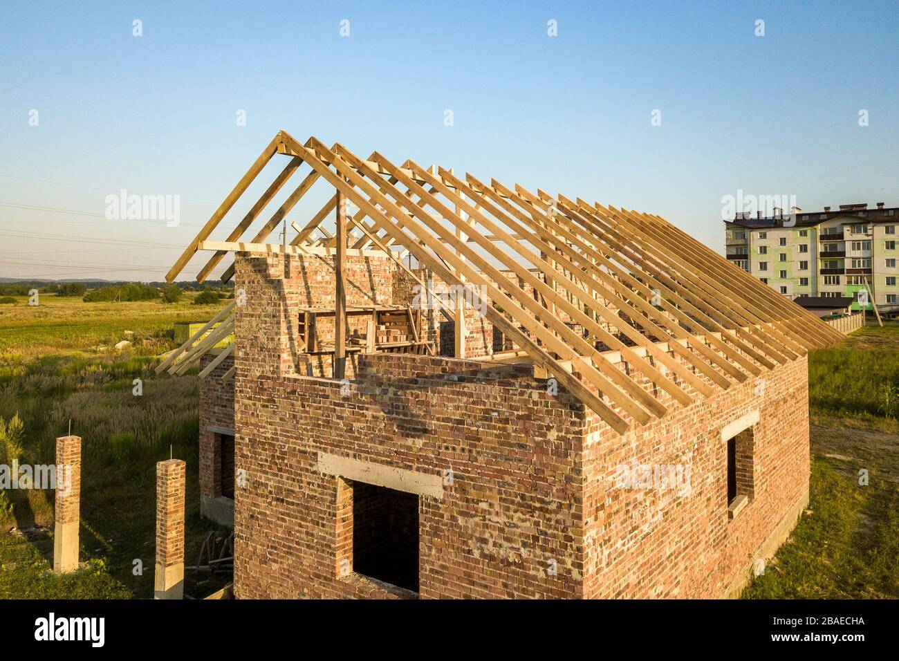 Unfinished brick house with wooden roof structure under construction ...