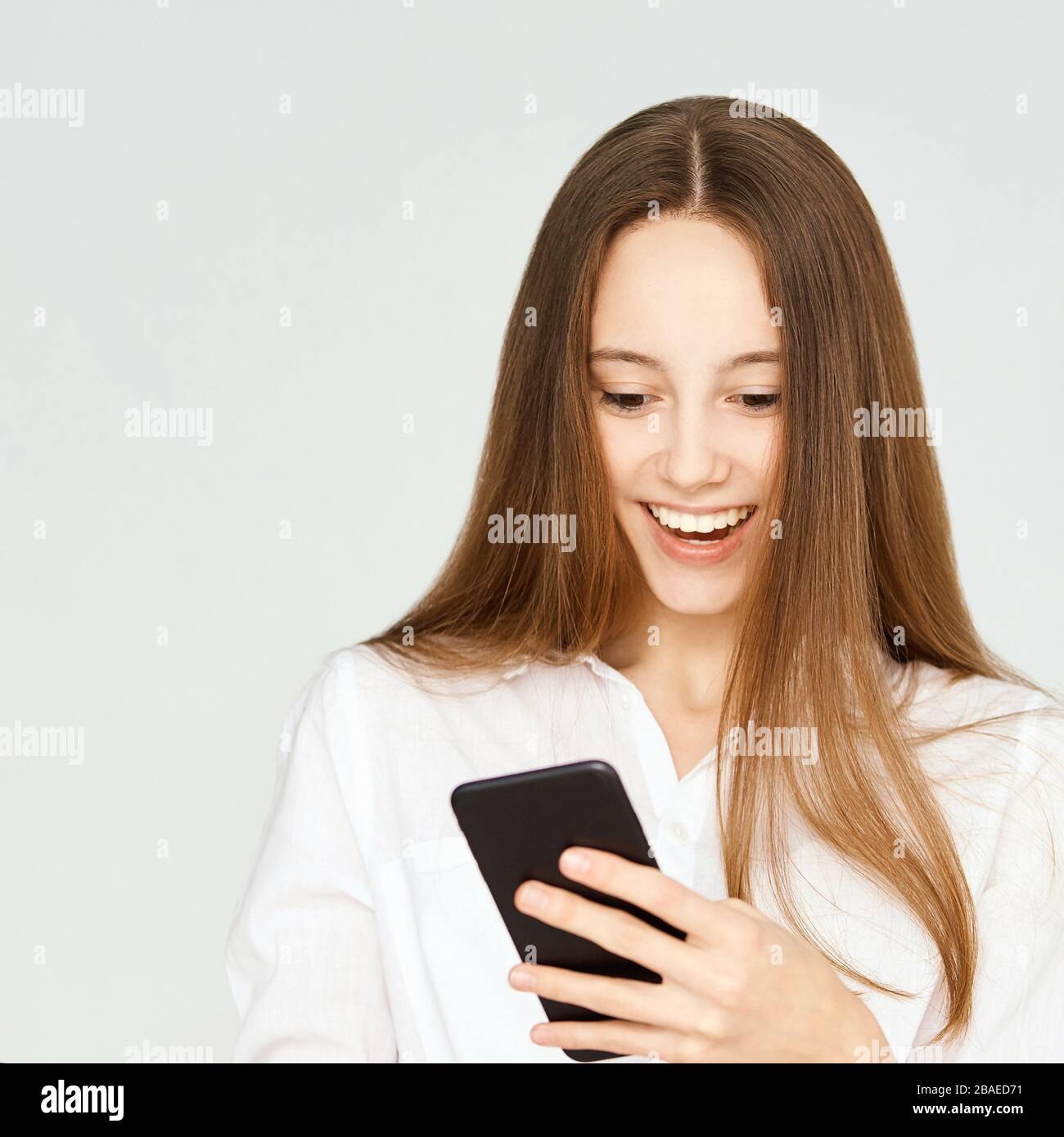 Happy young girl typing sms. Smartphone wow face. Female model at ...