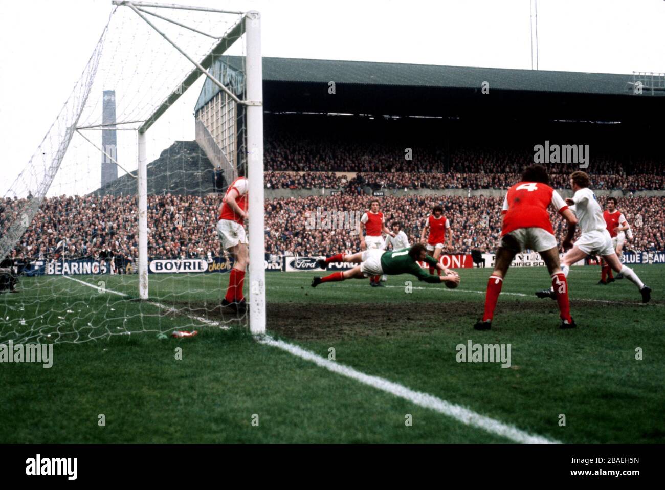 Arsenal goalkeeper Bob Wilson (c) dives to grab the ball as it fizzes ...