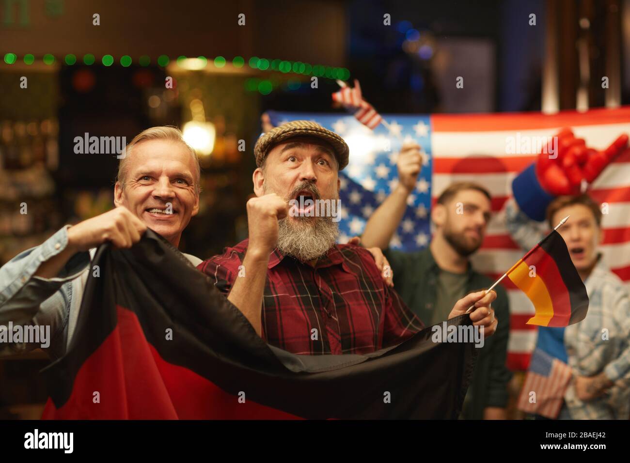 Mature men with German flag cheering for their football team while ...