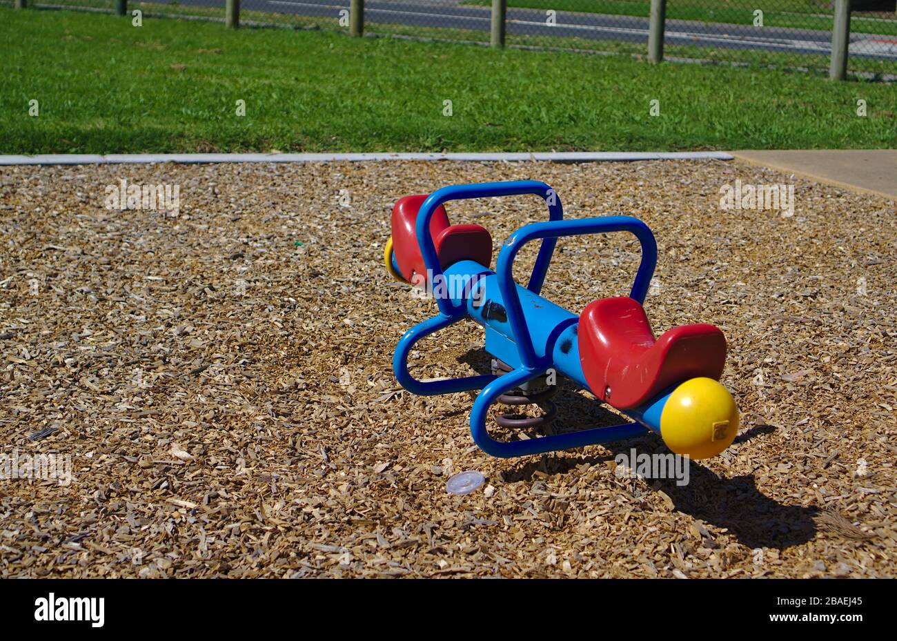 Children see saw in red, blue, and yellow colors on brown wooden pieces ...