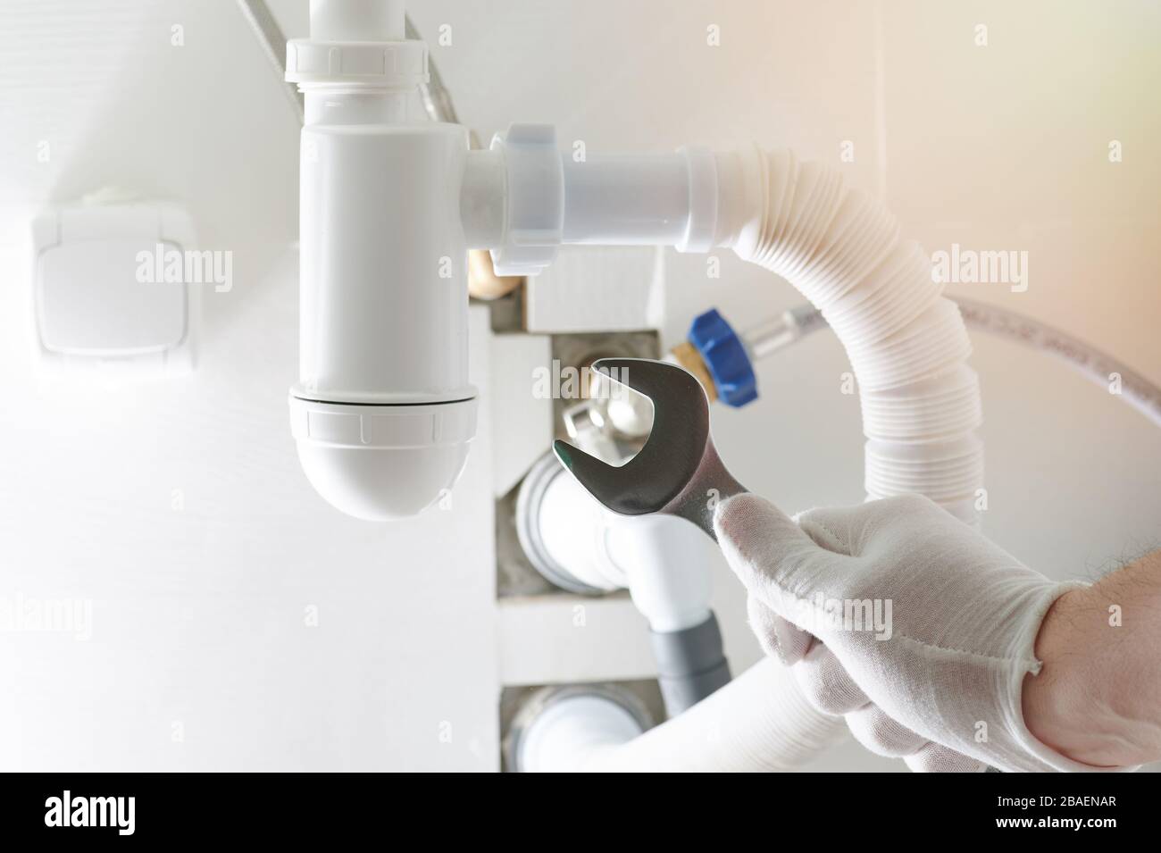 Plumber hand hold wrench on pipes sink background Stock Photo - Alamy