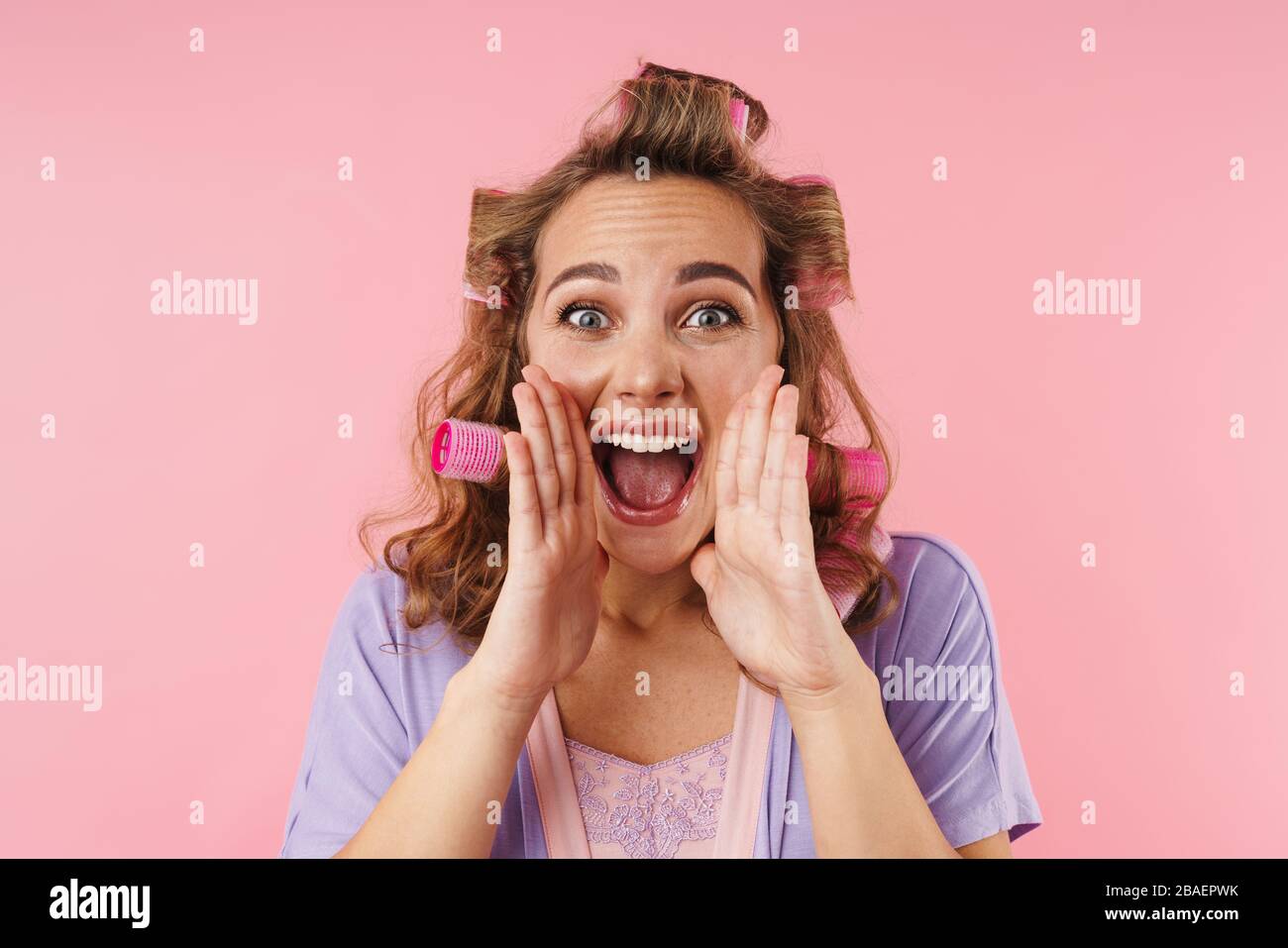Image of young excited woman in curlers screaming at camera isolated ...