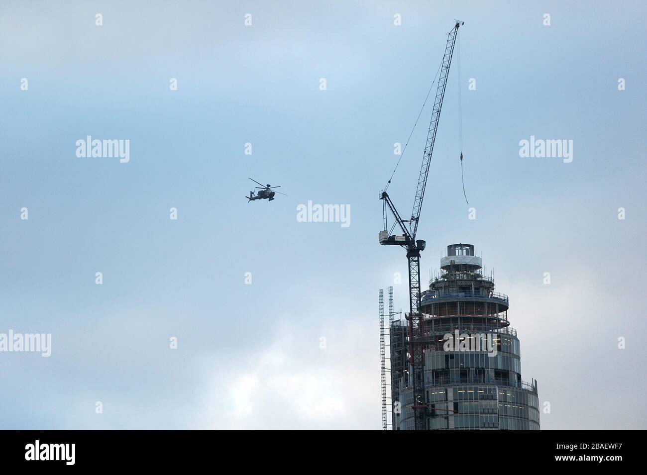 A military helicopter is seen flying past a high rise construction in ...