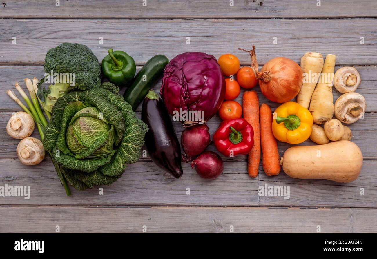 Selection of fresh vegetables arranged in a rainbow on a rustic ...