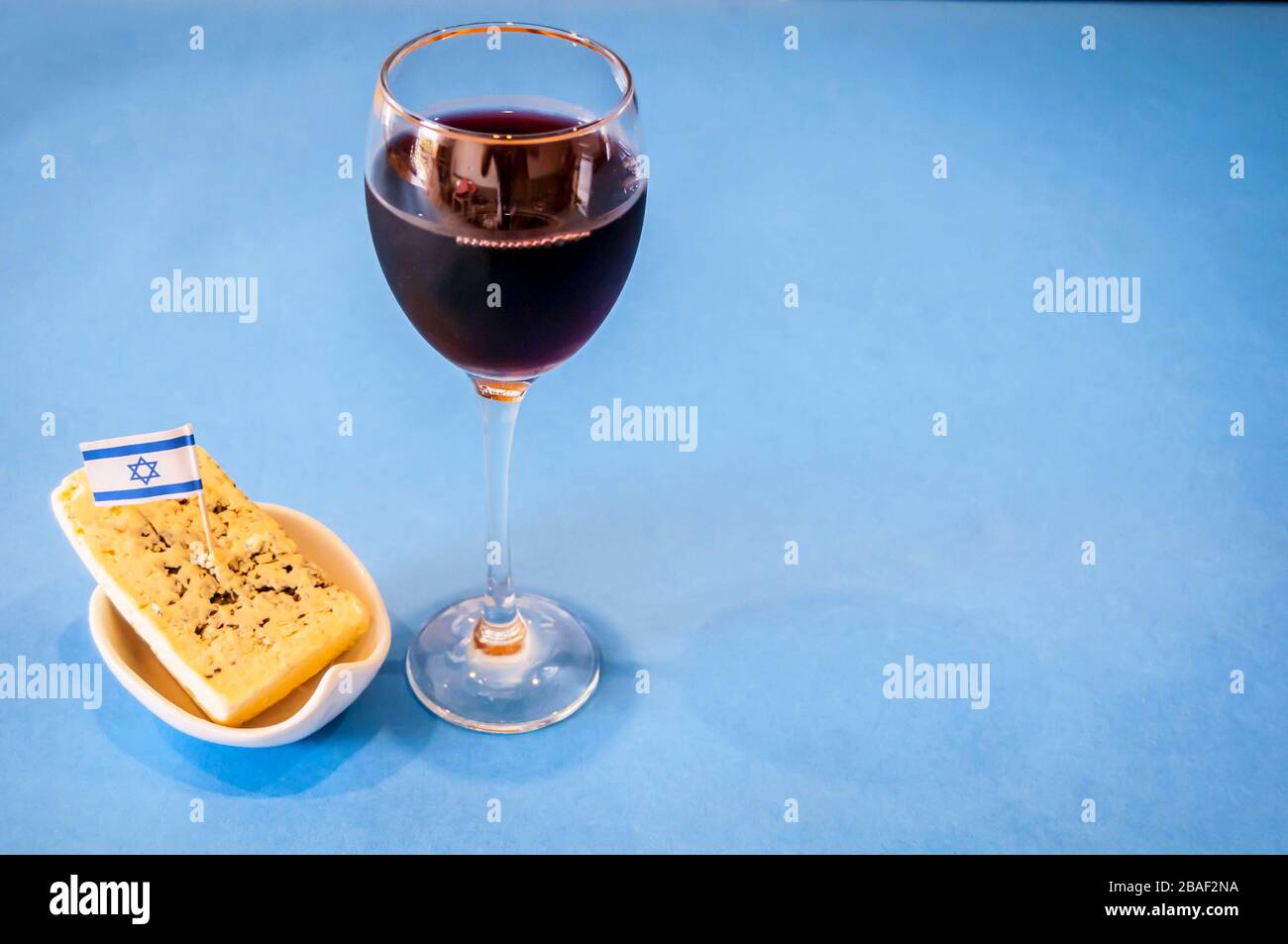 A glass of red wine with a piece of blue cheese on a small plate with a ...