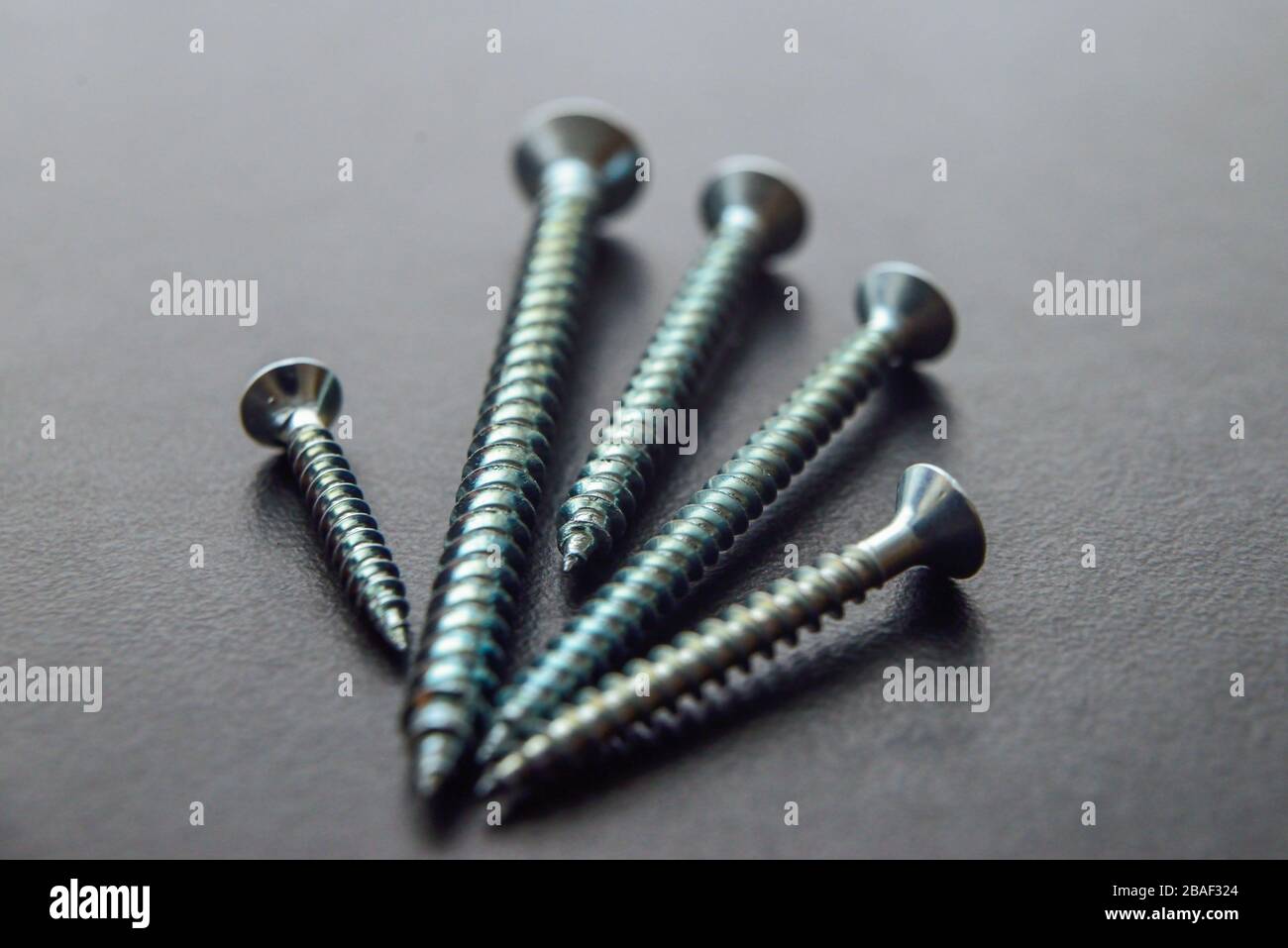 Five screws are on a black background Stock Photo - Alamy