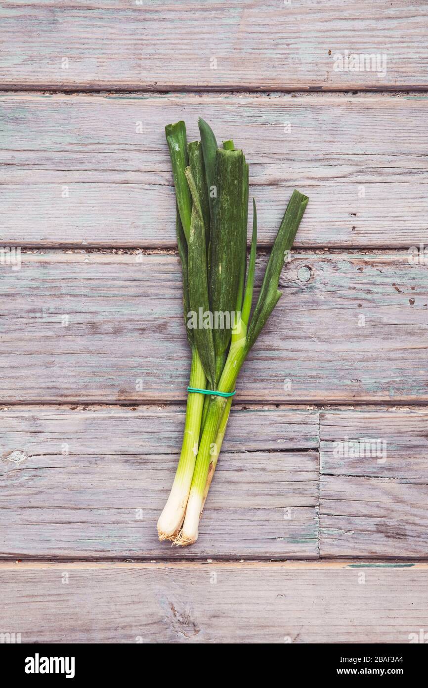 A bunch of fresh spring onions on a rustic wooden background Stock ...