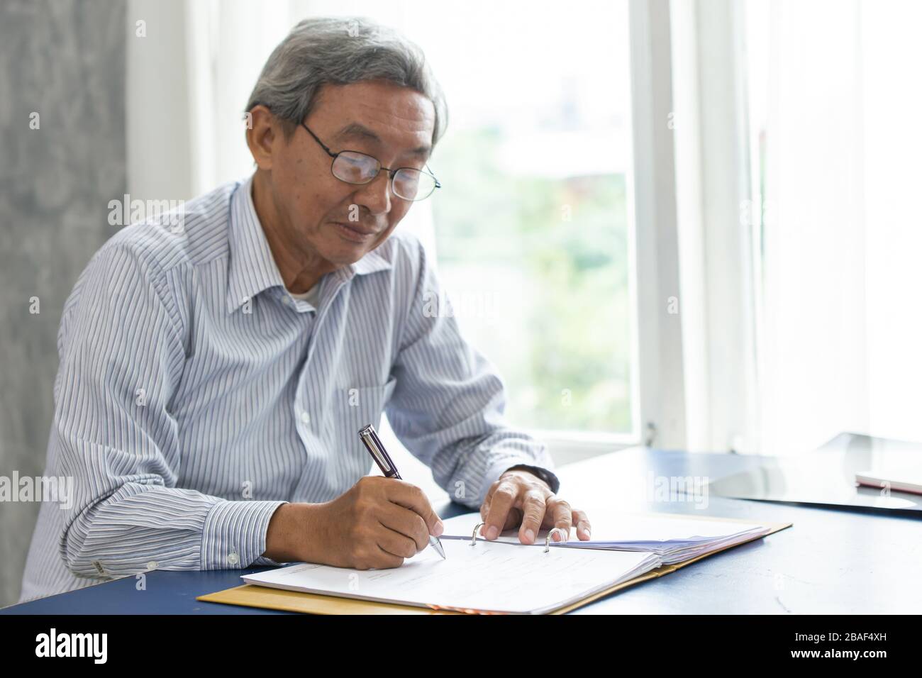 Asian smart business elder writing document report in the office Stock ...