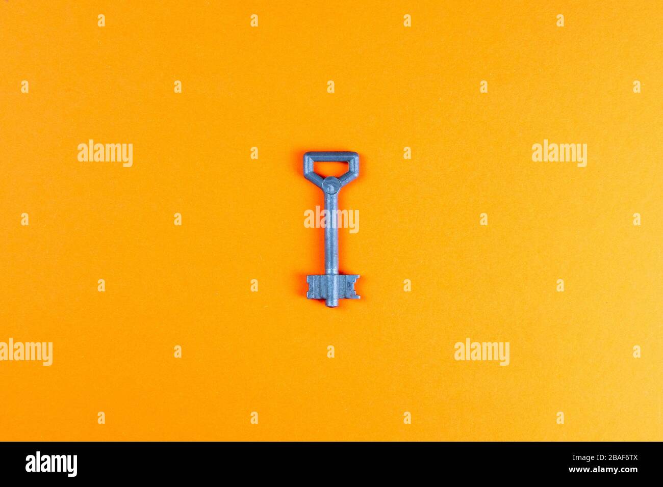 Metal old key on an orange background. Top views Stock Photo - Alamy