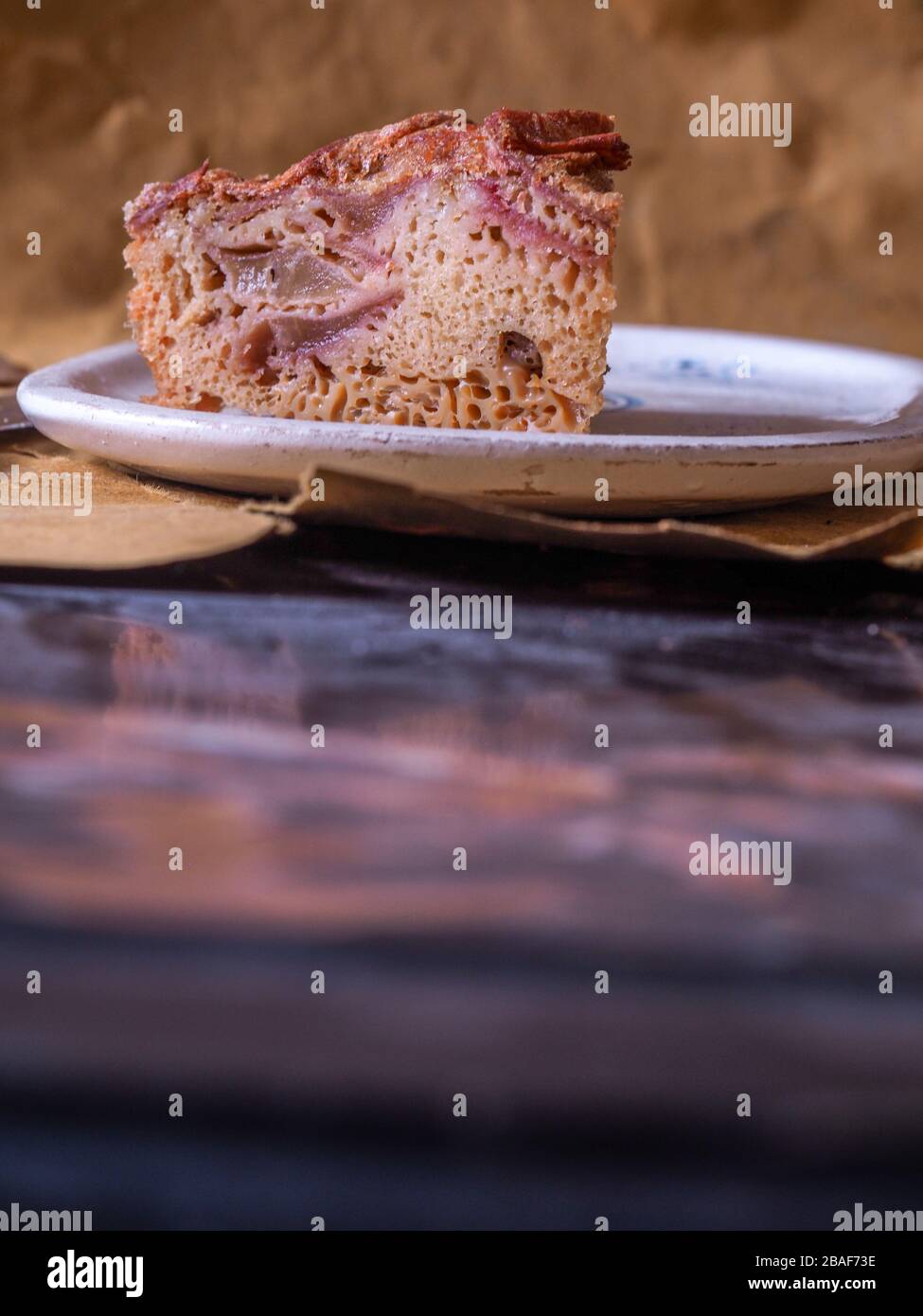 A photo of an whole flour apple pie in allu foil, on a dark rustic ...