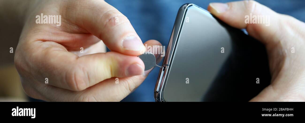 Male hands getting sim card slot of his smartphone out Stock Photo - Alamy