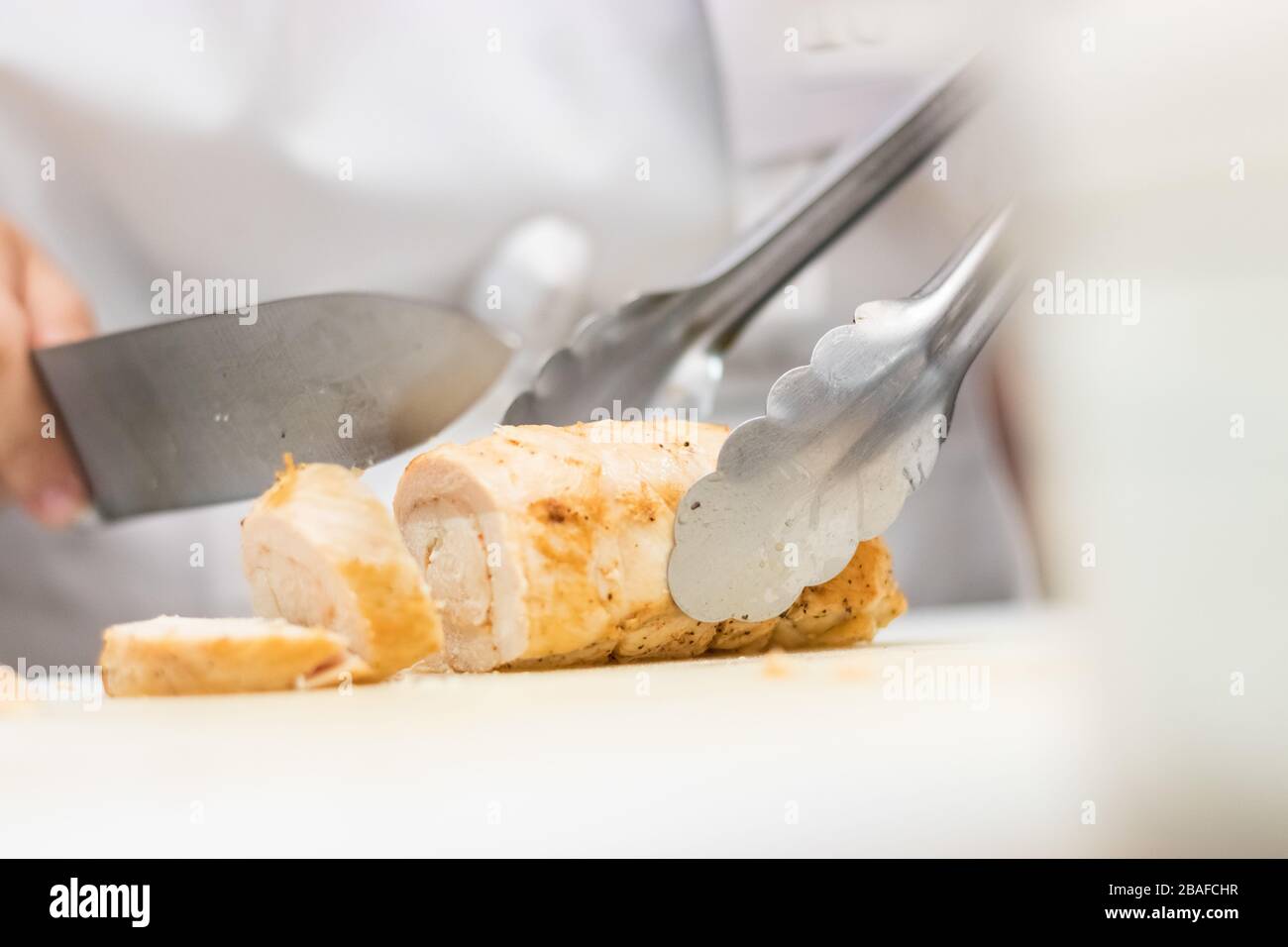 Professional chief cutting a fish roll into slices in a kitchen Stock ...