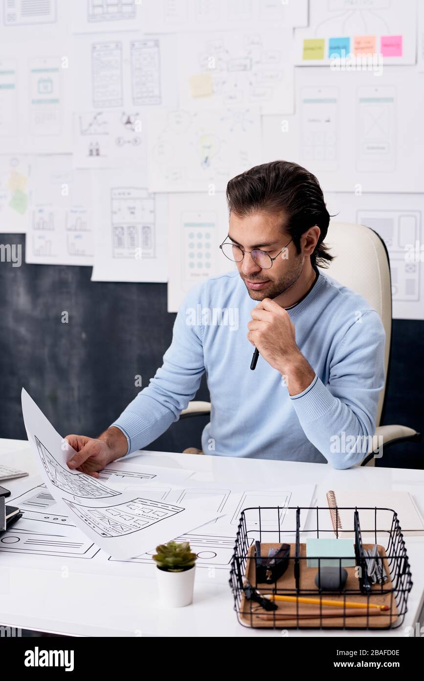 Serious middle-aged man in glasses sitting at desk and watching ...
