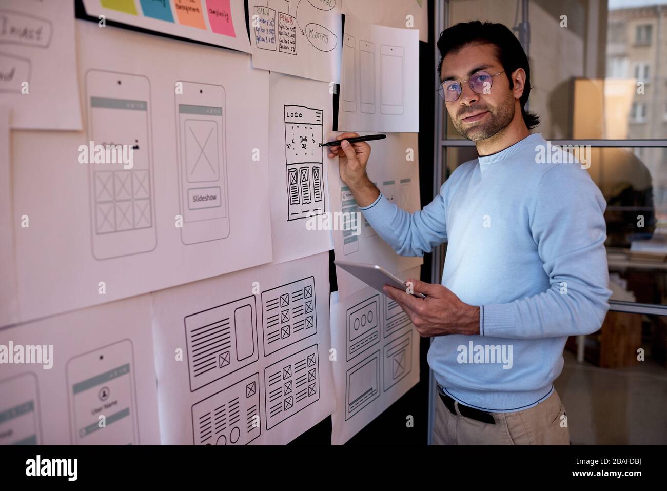 Portrait of handsome user interface designer with stubble standing at ...