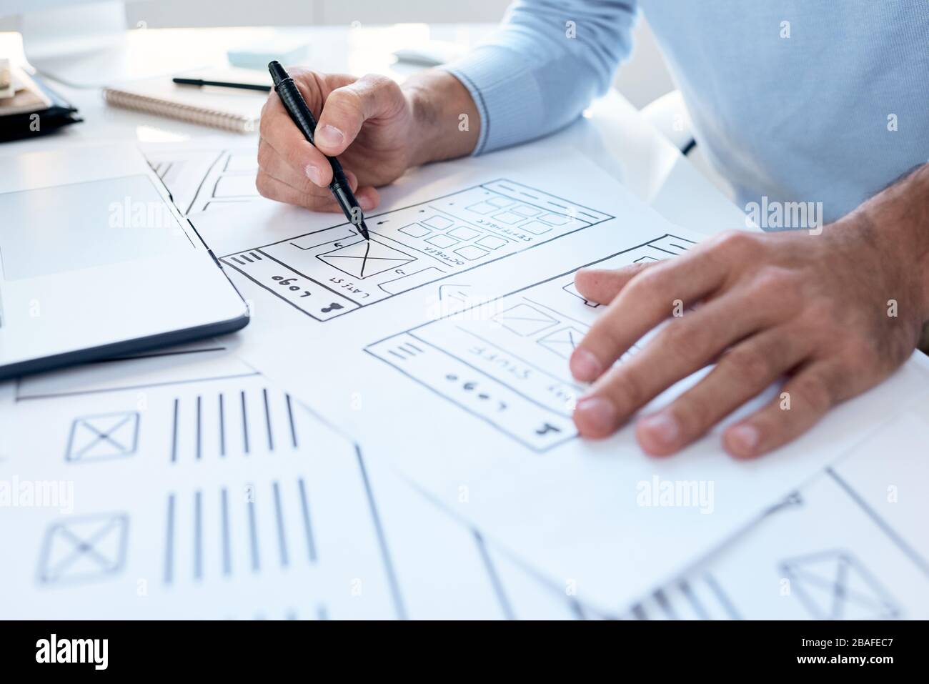 Close-up of unrecognizable UI engineer sitting at desk and making ...