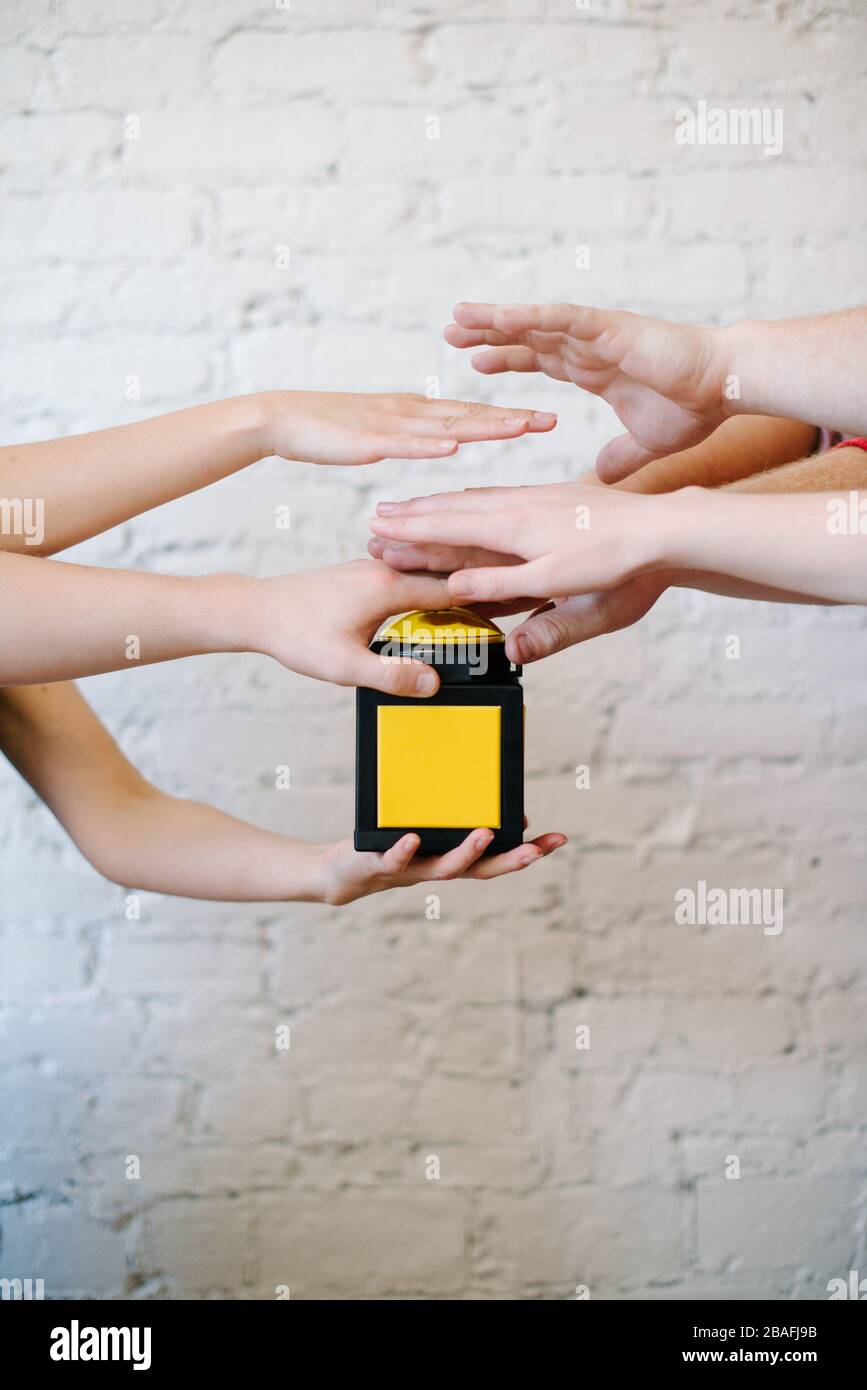 many hands reaching to press yellow buzzer button against white brick ...
