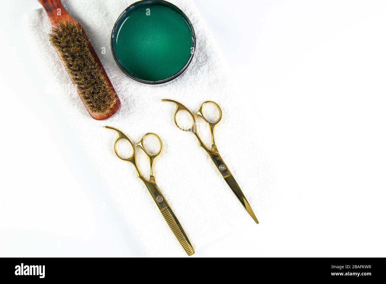 Hair gel, comb and scissors for haircut stand on a white towel which ...