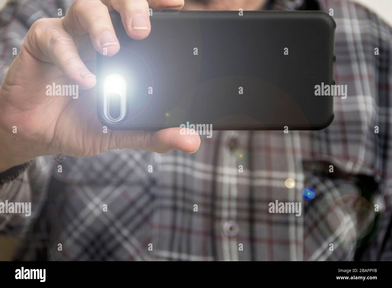 Man holding cell phone while camera flash goes off. Lens flare is ...