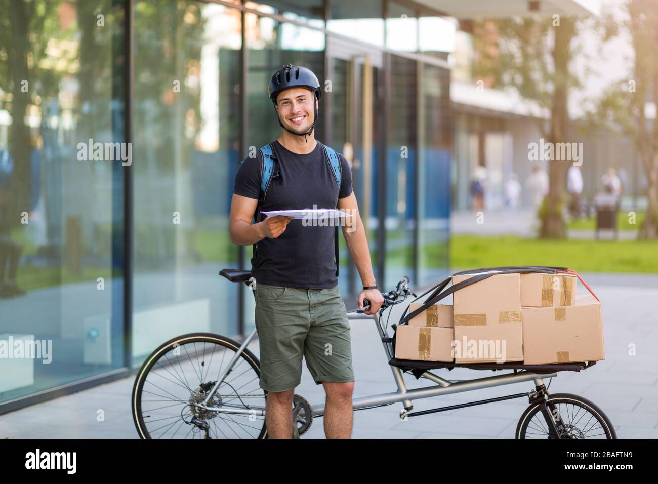 Bicycle messenger making a delivery on a cargo bike Stock Photo - Alamy