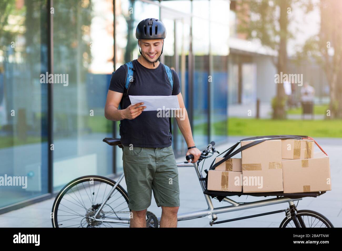 Bicycle messenger making a delivery on a cargo bike Stock Photo - Alamy