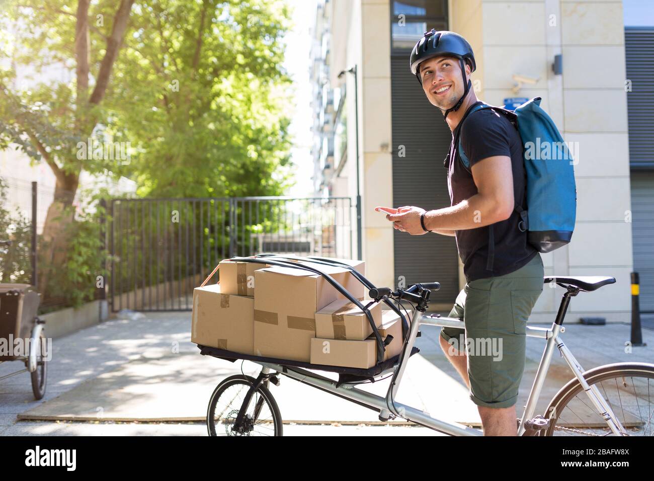 Bicycle messenger making a delivery on a cargo bike Stock Photo - Alamy