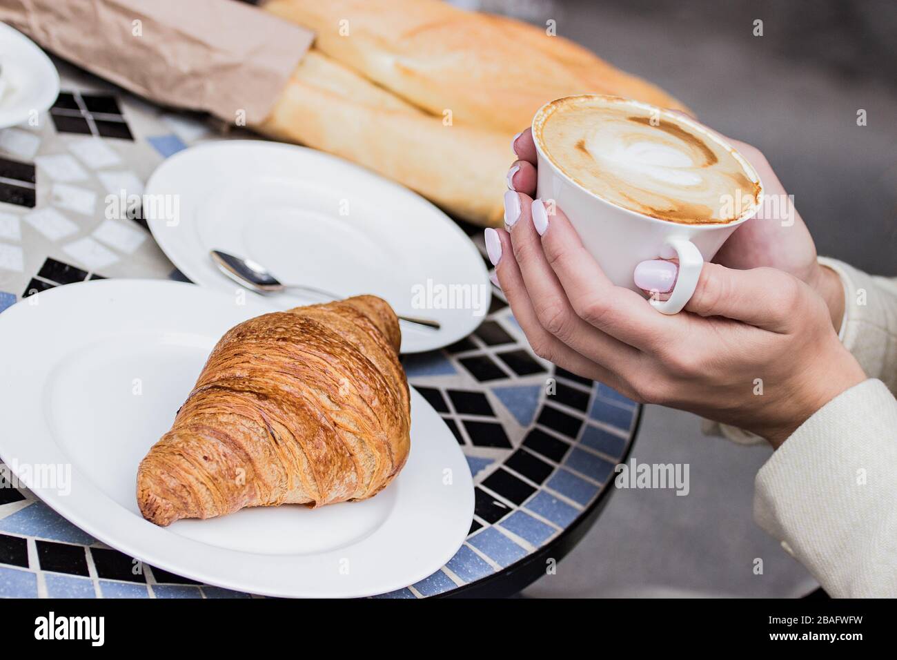 French breakfast concept. Closeup of woman's hands holding cup of ...