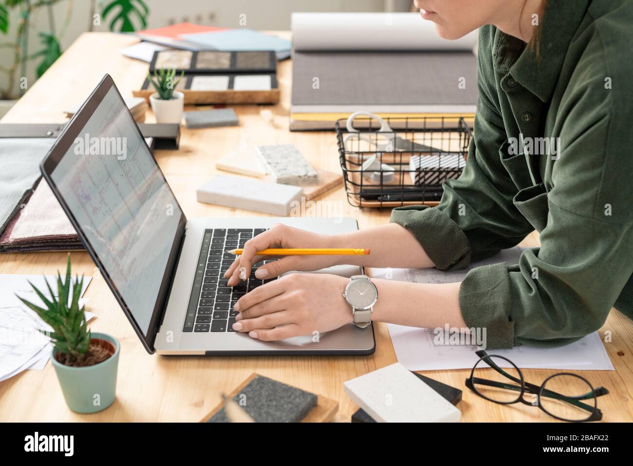 Young creative female designer bending over desk in front of laptop ...