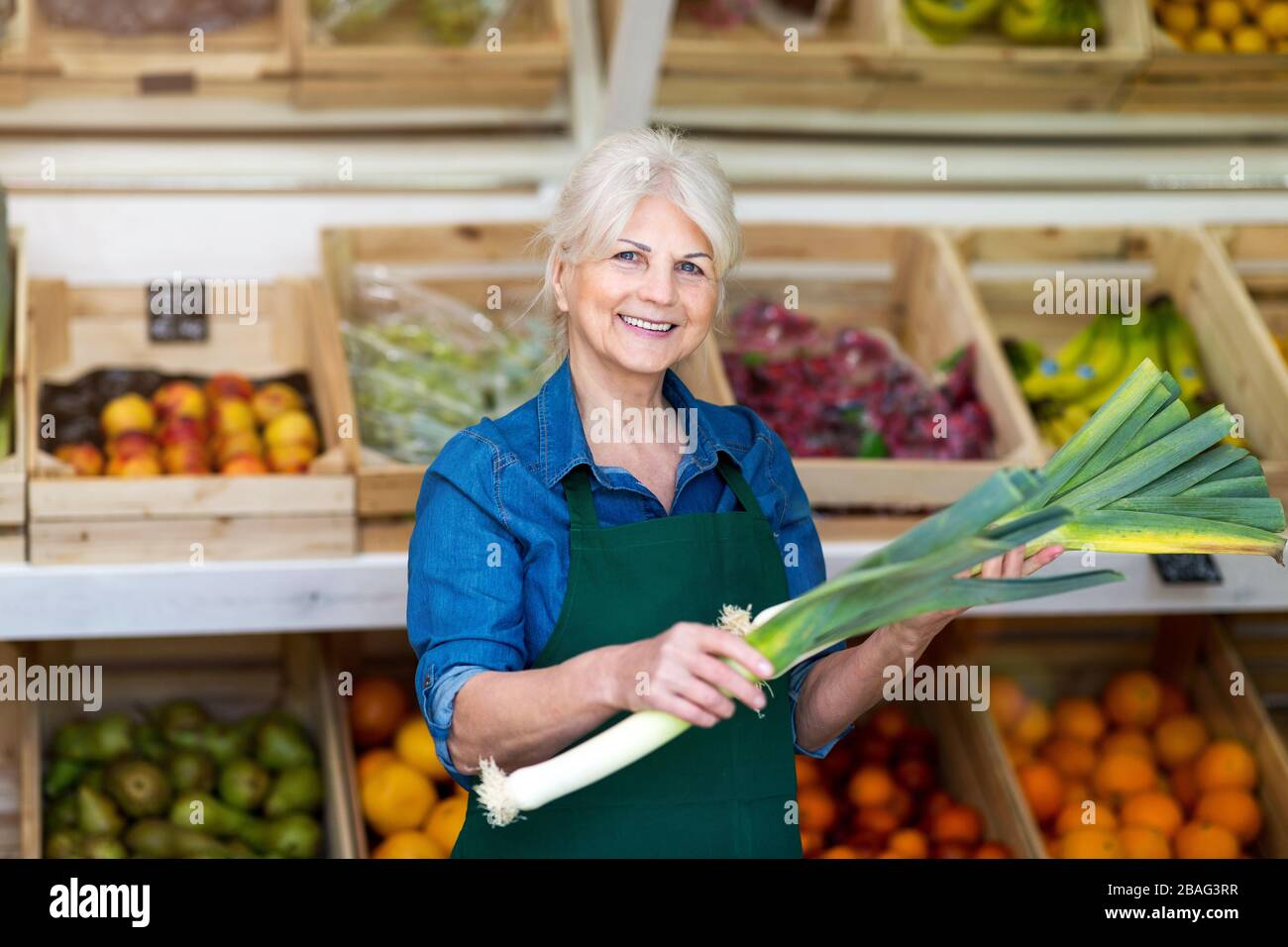 Senior woman working in small grocery store Stock Photo - Alamy
