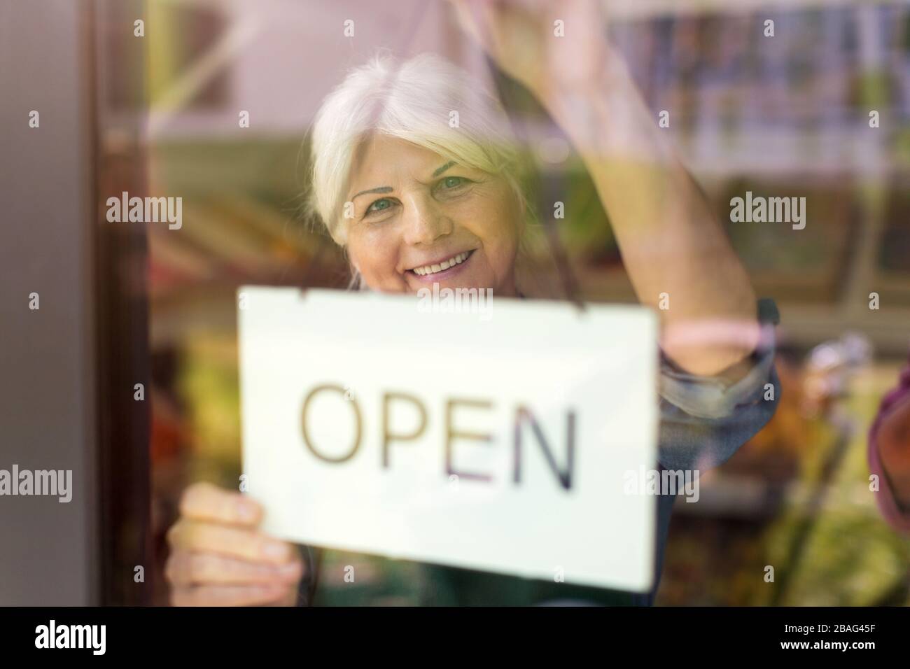 Senior woman working in small grocery store Stock Photo - Alamy