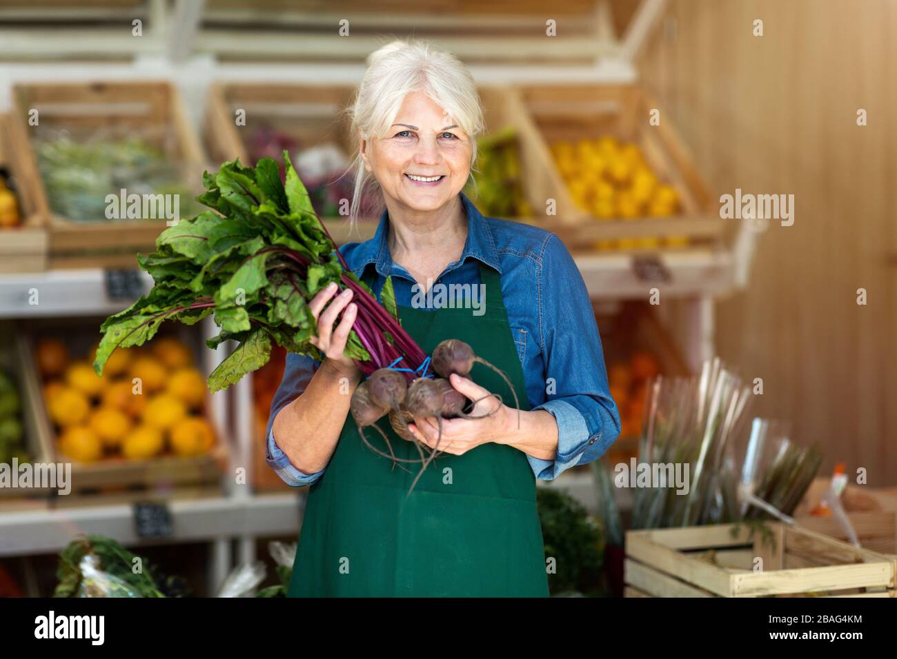 Senior woman working in small grocery store Stock Photo - Alamy