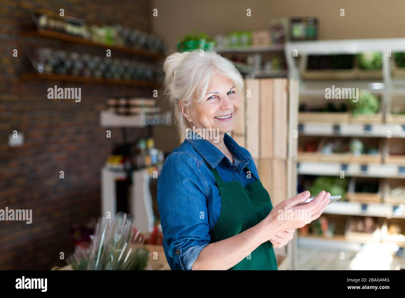 Senior woman working in small grocery store Stock Photo - Alamy