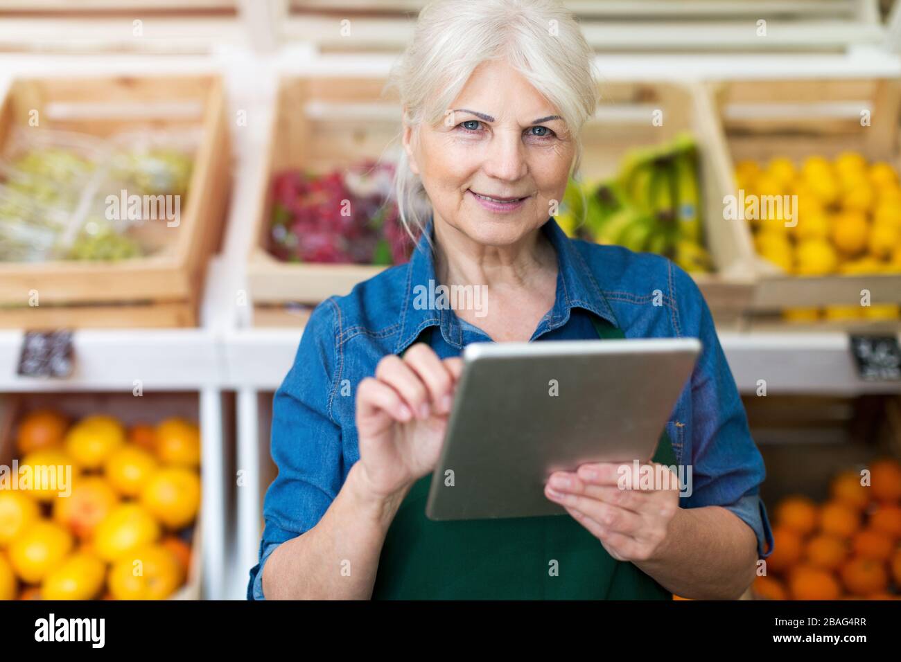 Senior woman working in small grocery store Stock Photo - Alamy