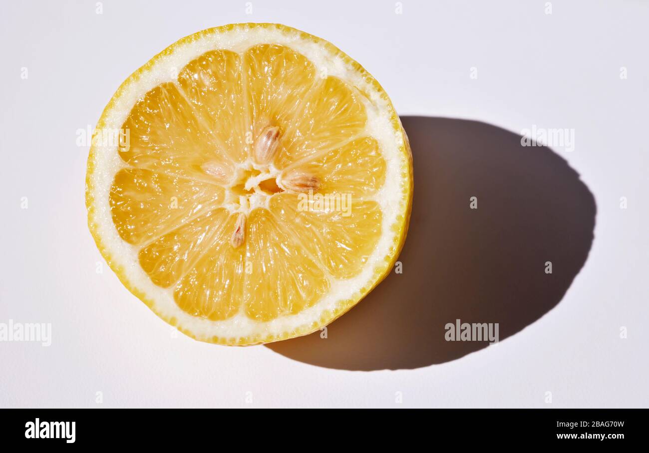 Beautiful slice of lemon with dark shadow on white background , studio ...