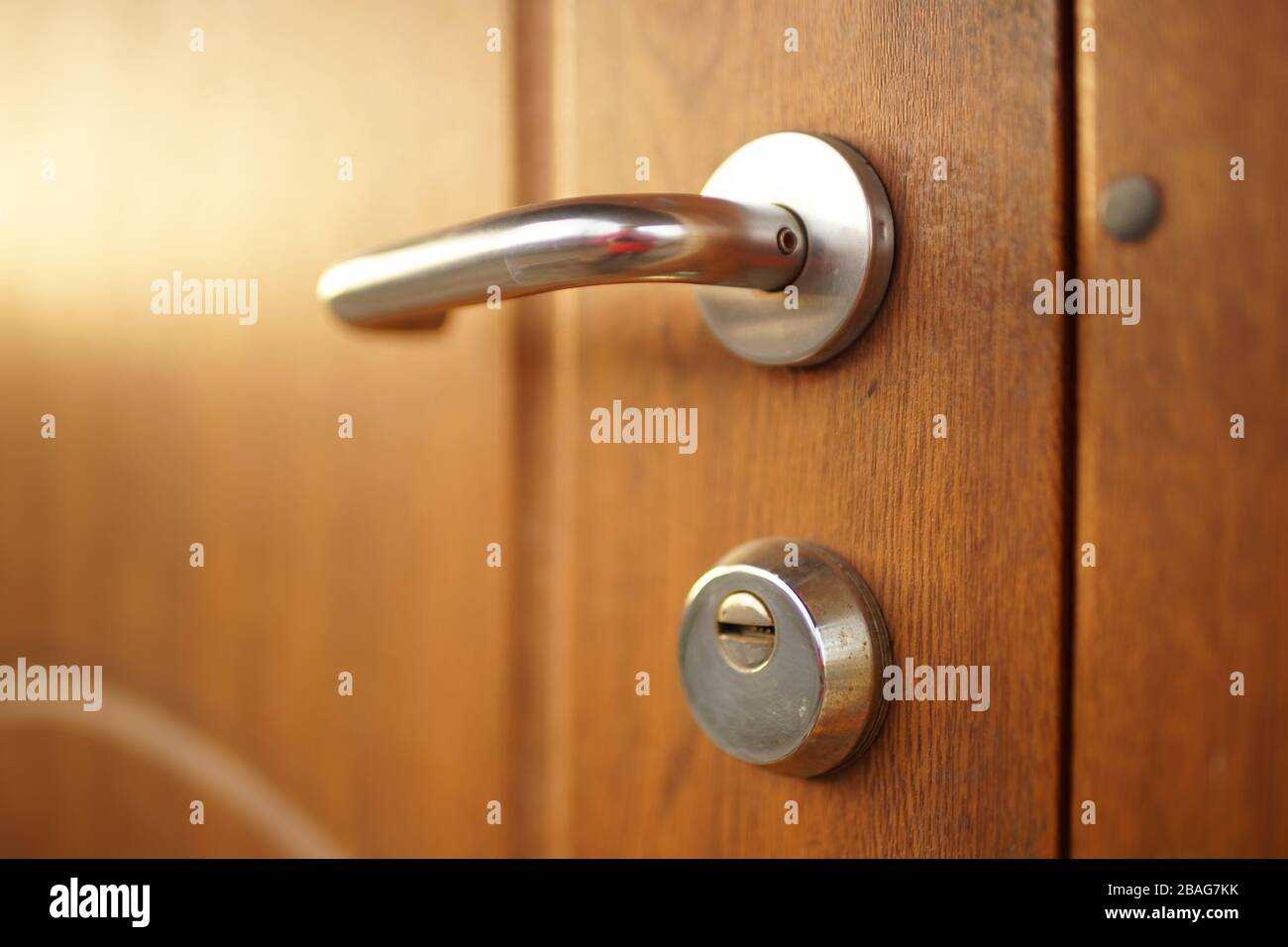 Shiny brown wooden door with chrome handle and keyhole, side view ...
