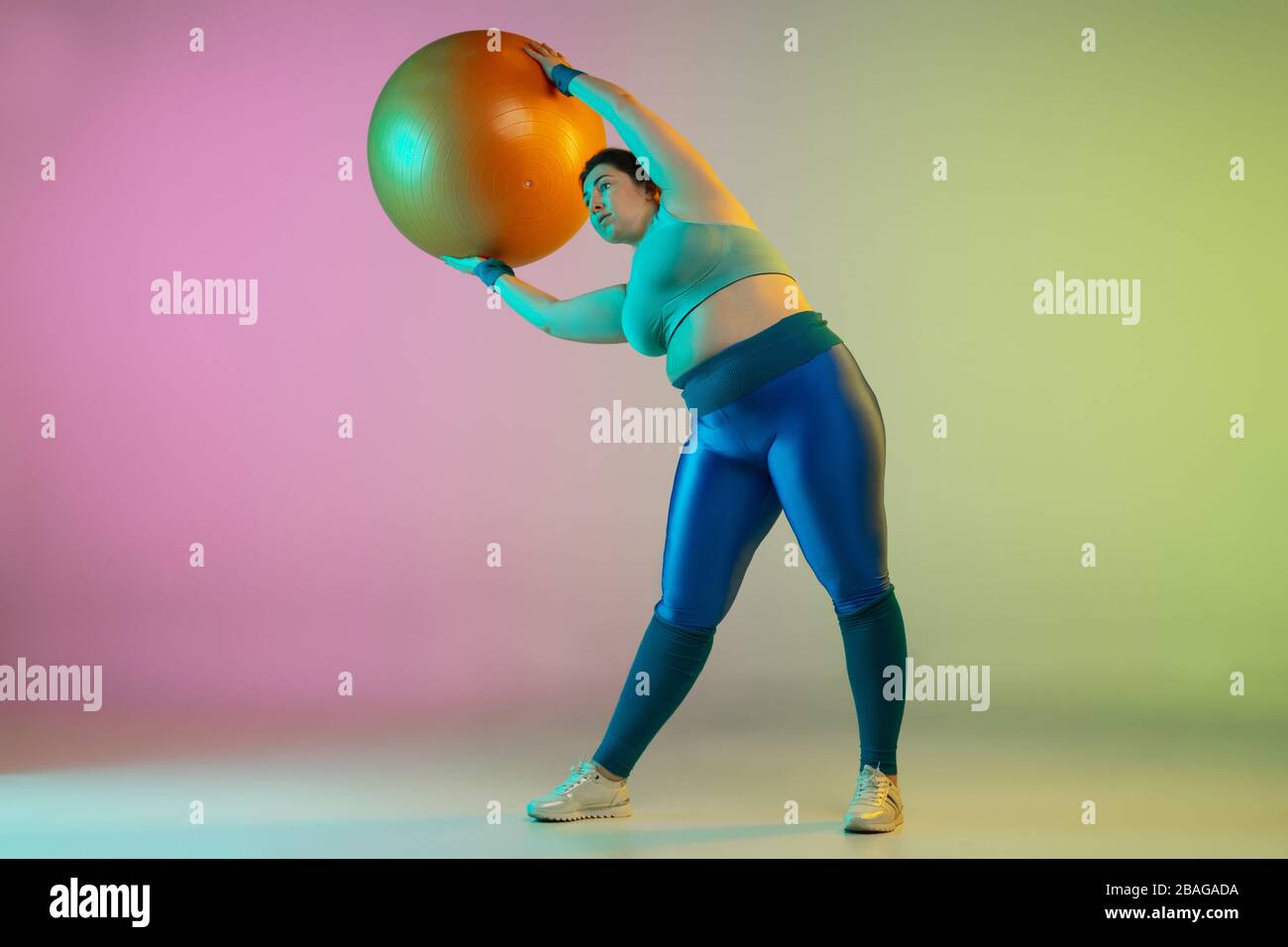 Young caucasian plus size female model's training on gradient purple ...