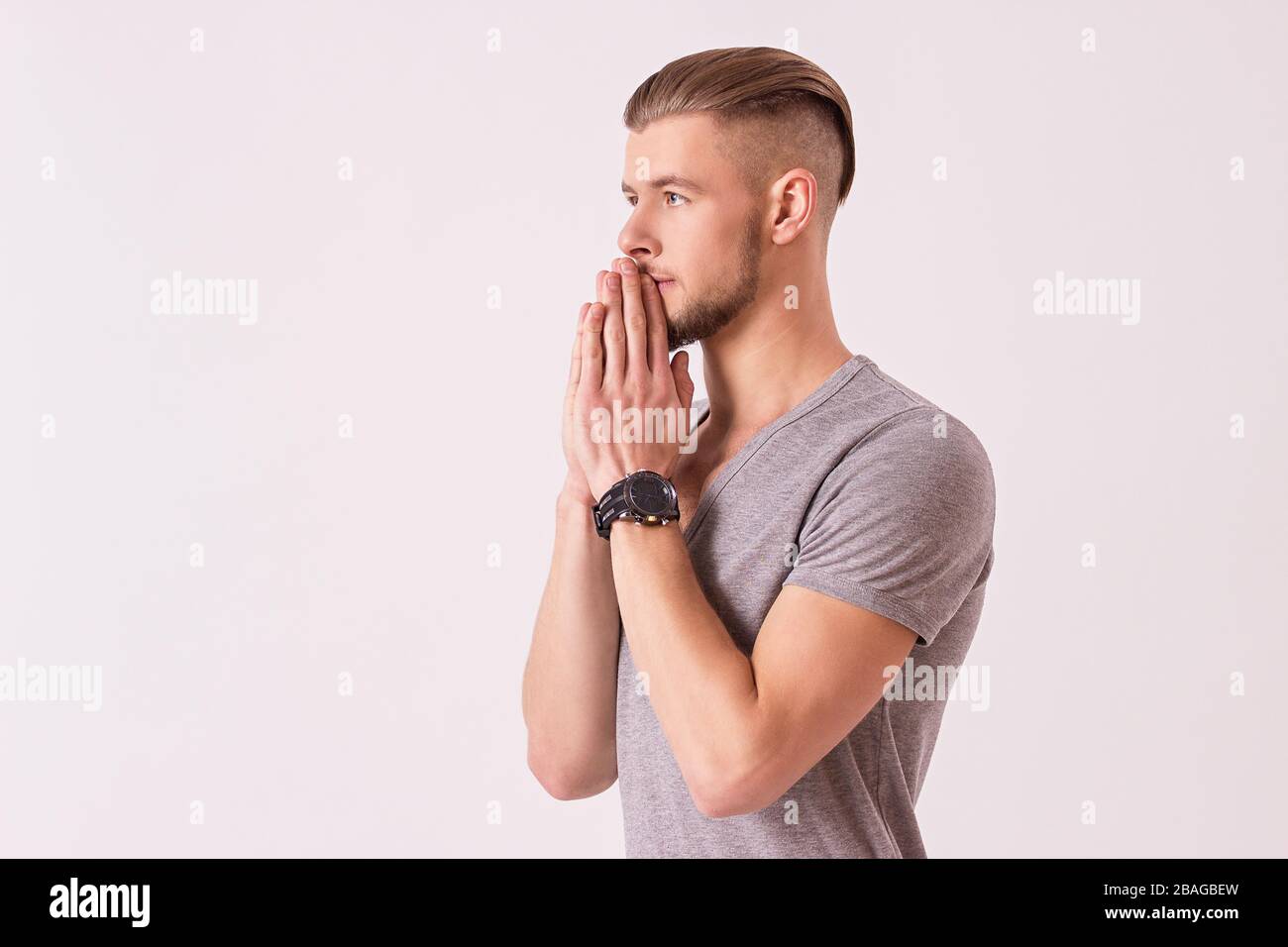 Studio shot of pensive hipster man praying and looking away while ...